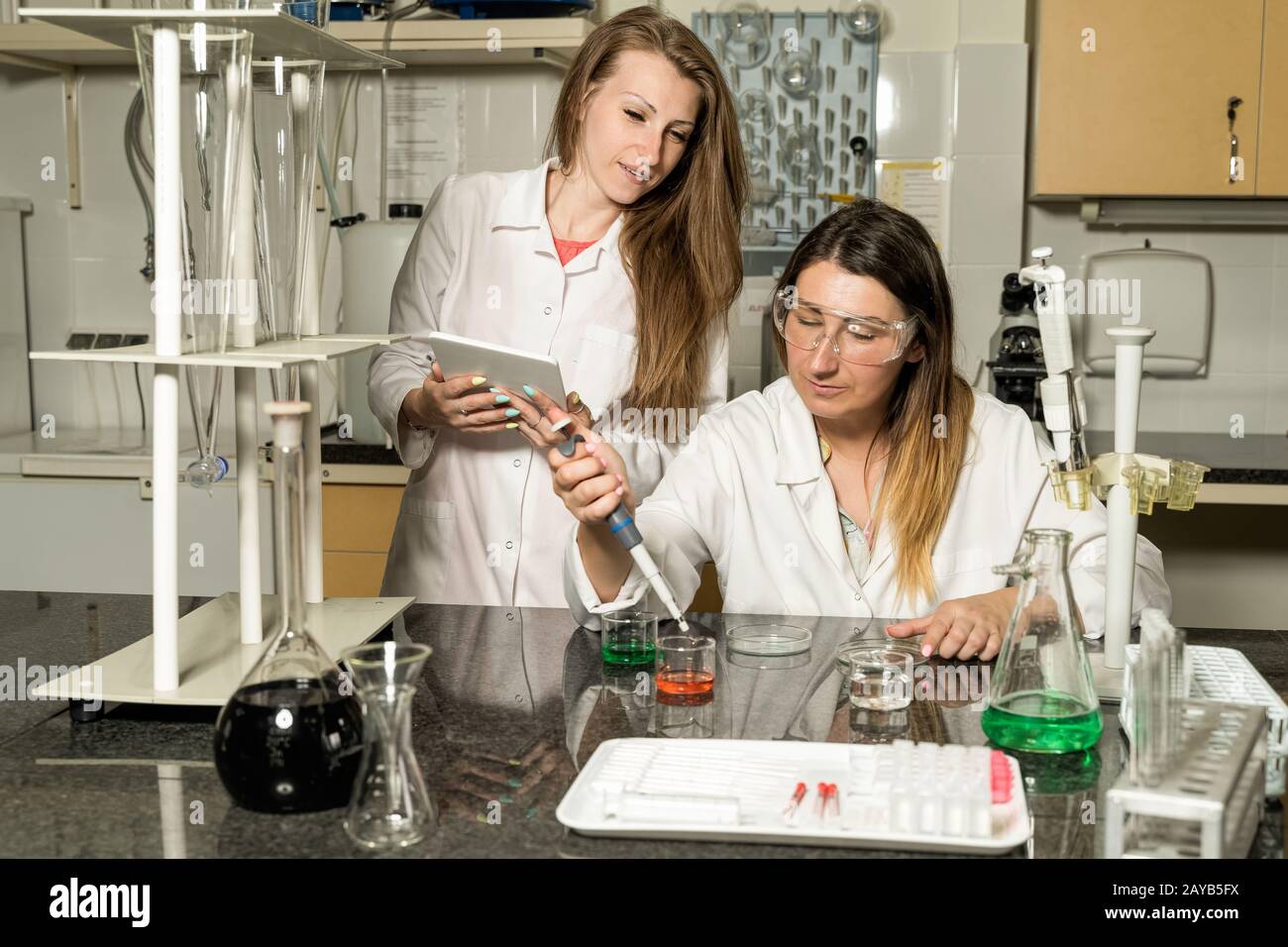 Team of two female laboratory technicians working in chemical or ...