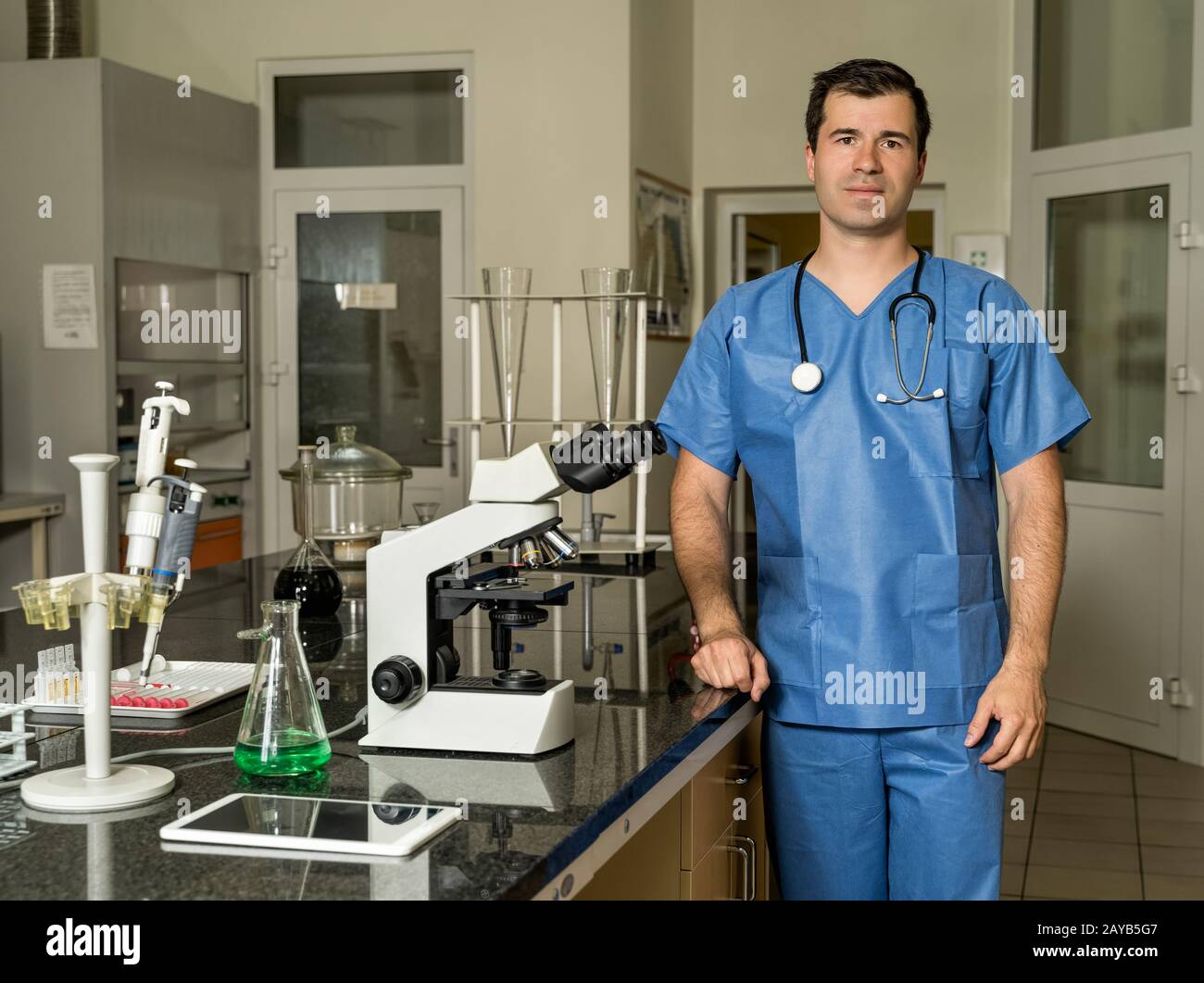 Middle age male laboratory technician standing next to compound ...