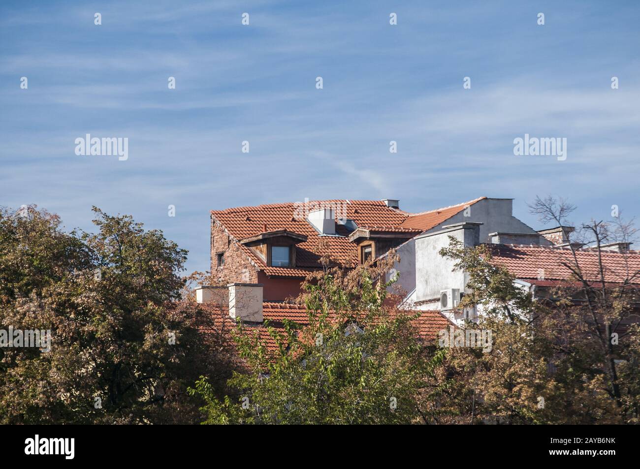 Red tiled house roof tops on blue sky background Stock Photo - Alamy