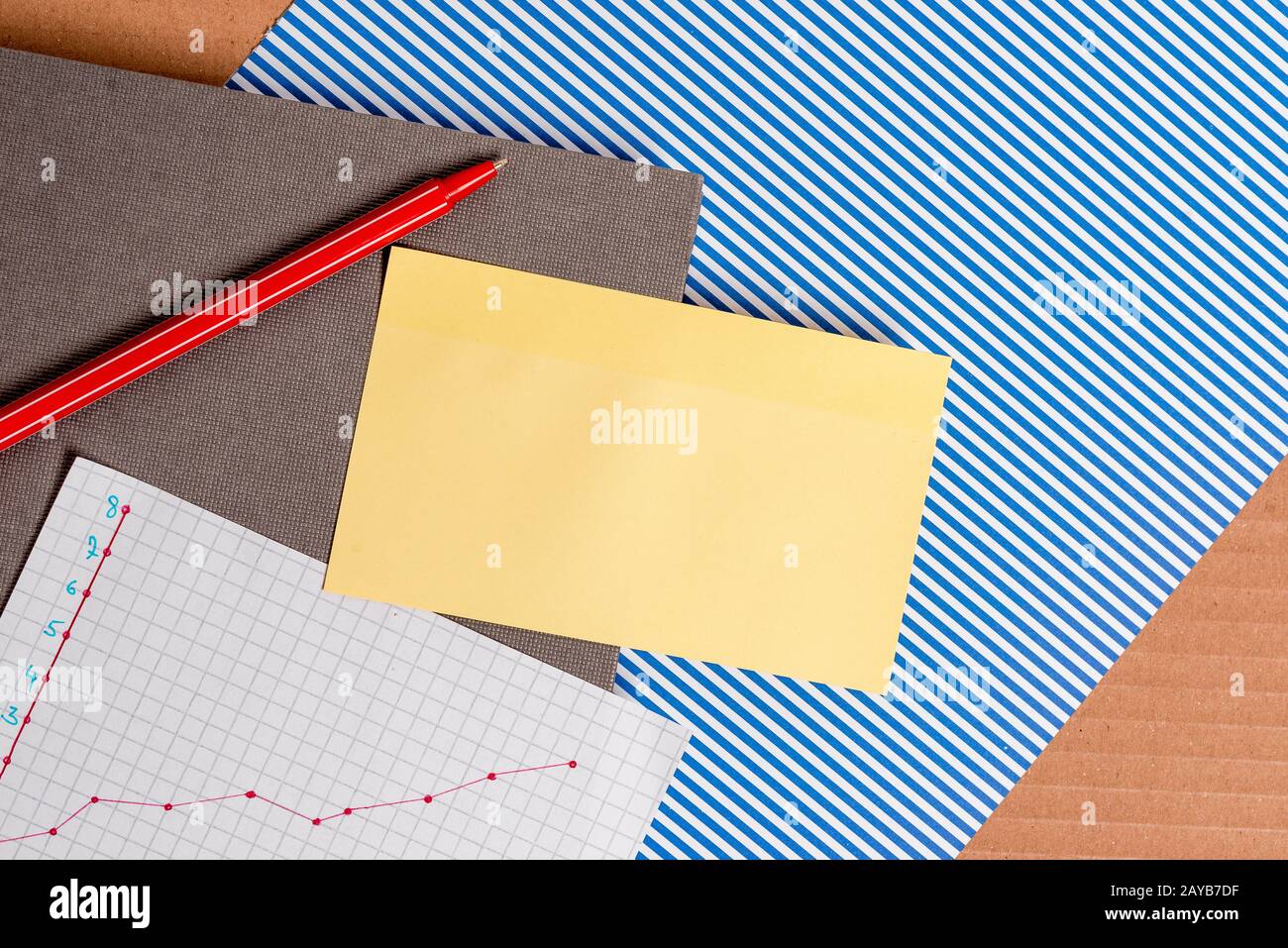 Cardboard desk with a striped blue sheet, notebook paper and office ...