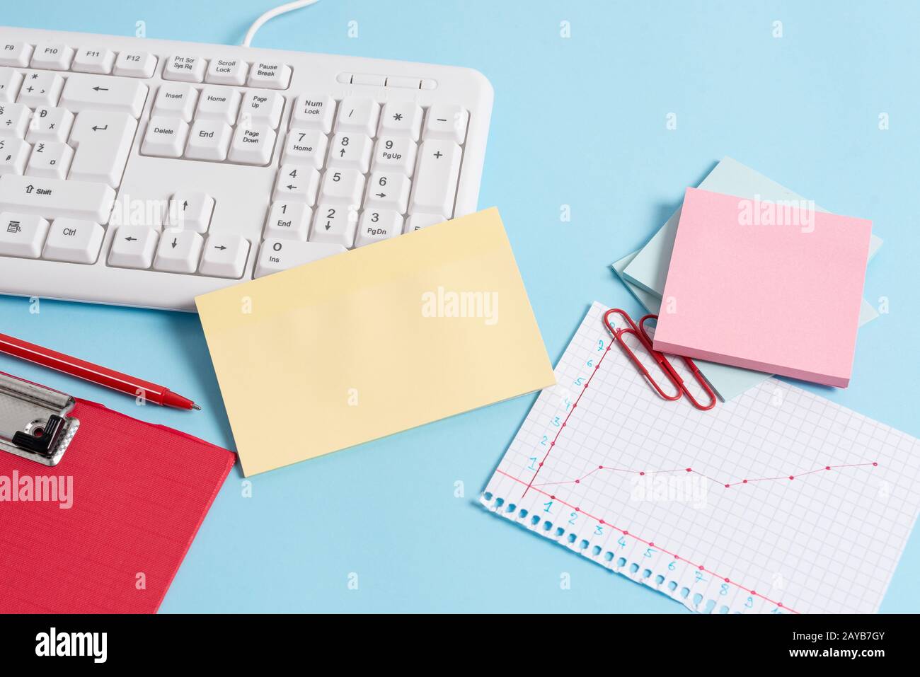 Light blue desk with different sizes of empty paper notes, computer ...