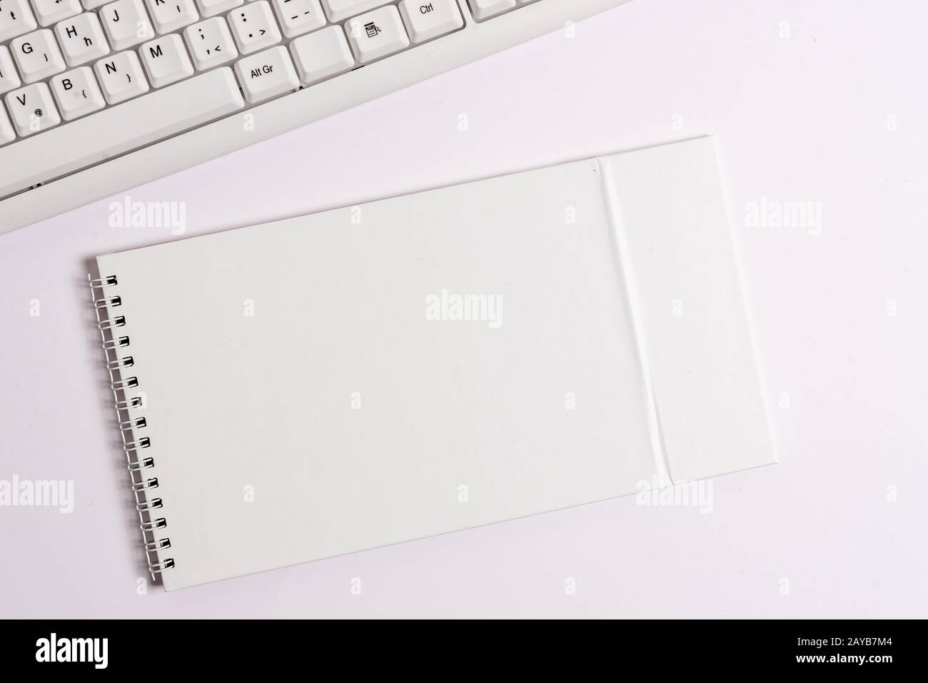 White pc keyboard with empty note paper above white background ...