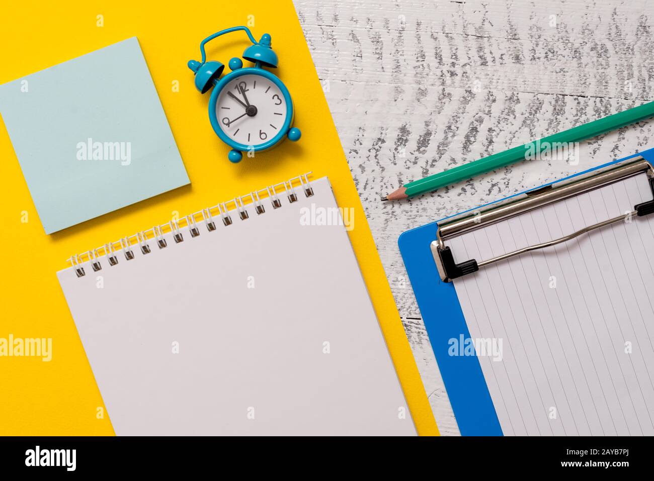 Closeup front view blank spiral notepad pencil small alarm clock letter ...