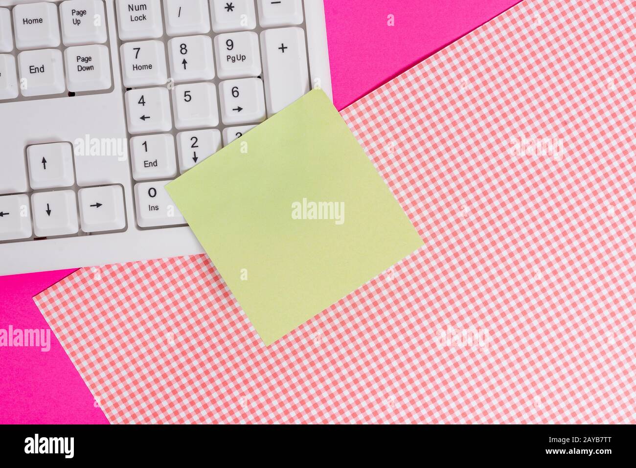 Note sheet sticked to computer keyboard near patterned fabric above a ...
