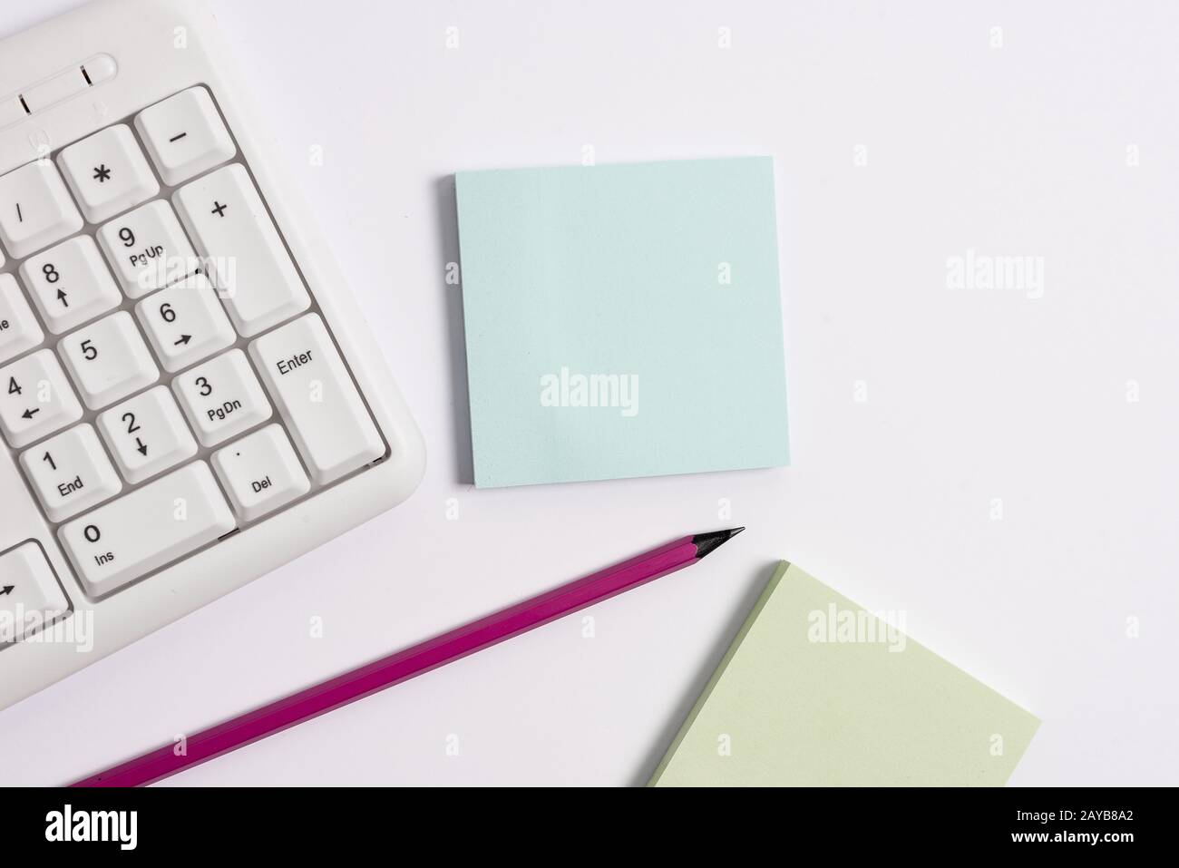 White pc keyboard with empty note paper and pencil above white ...