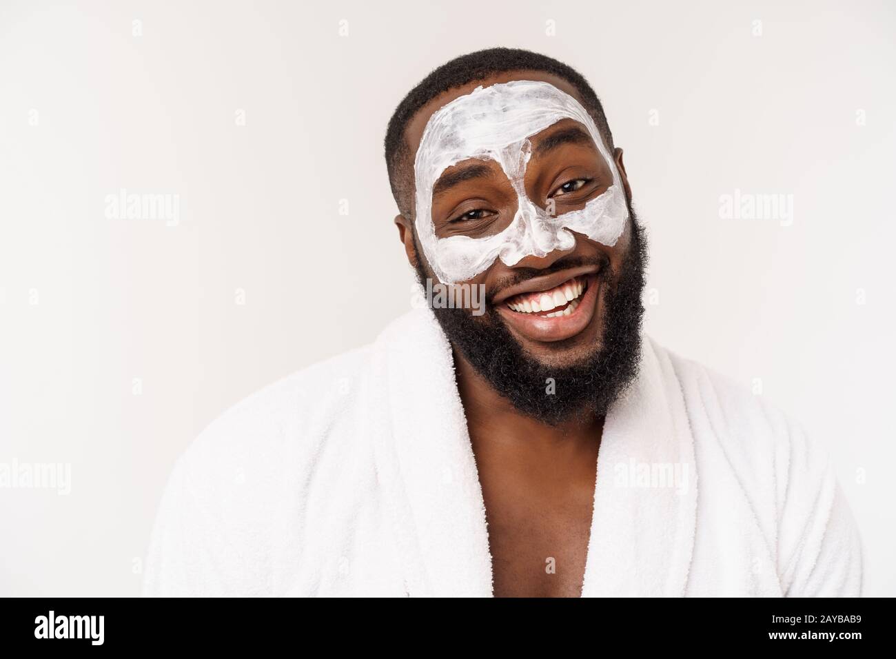 Young african-american guy applying face cream on white background ...
