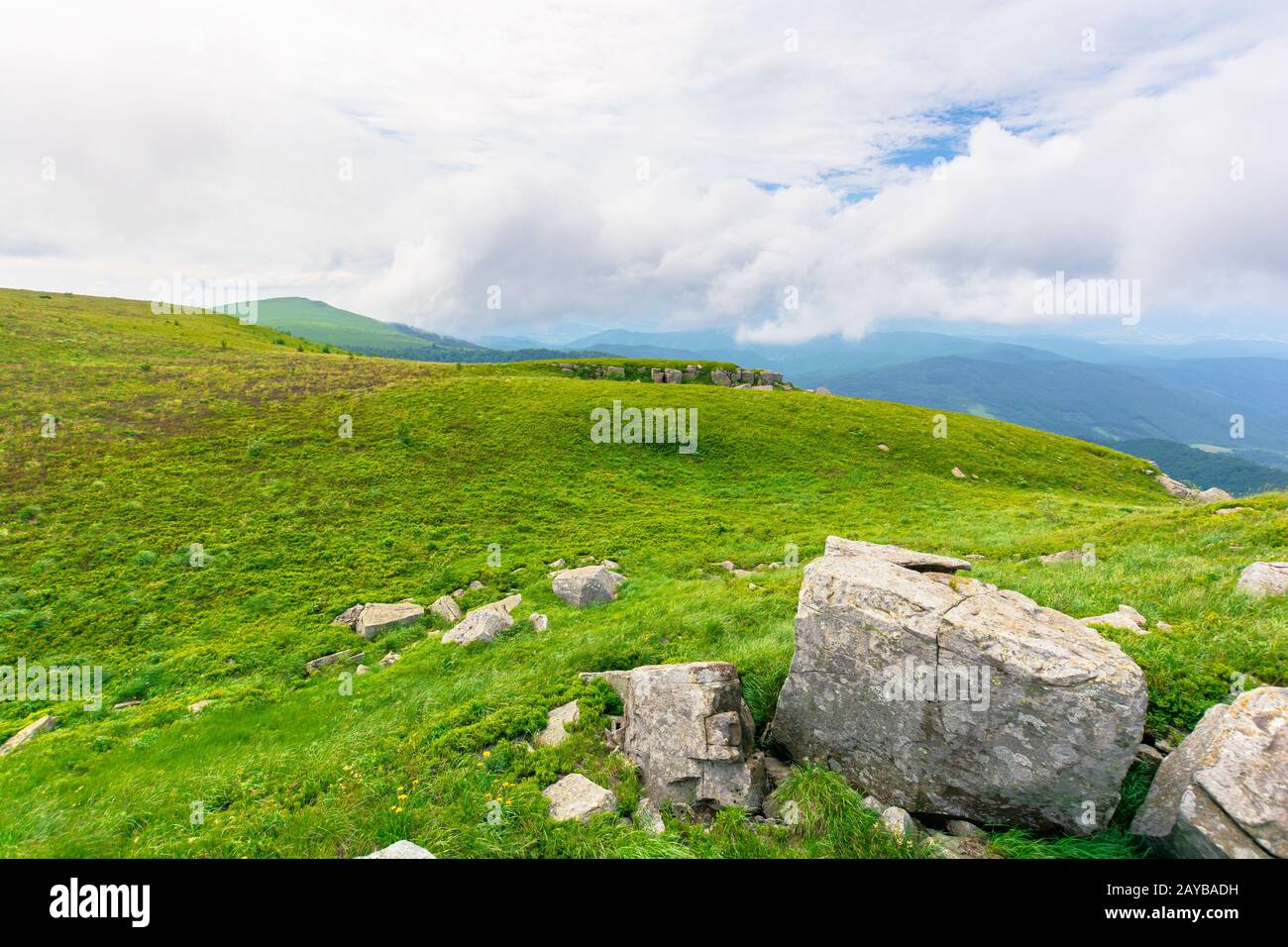 rock on the meadow. cloudy alpine summer. grass on the hills, slopes ...