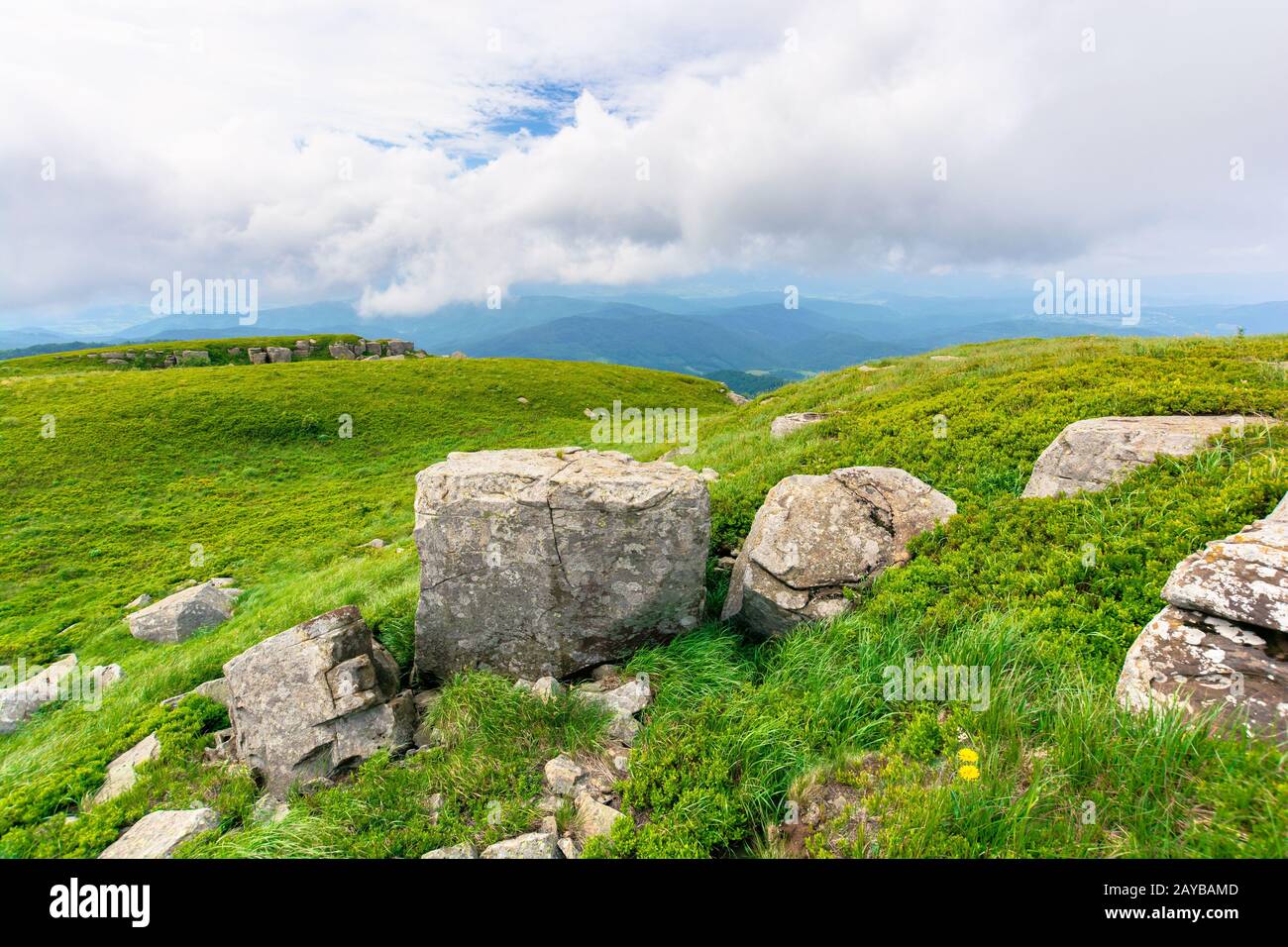 rock on the meadow. cloudy alpine summer. grass on the hills, slopes ...
