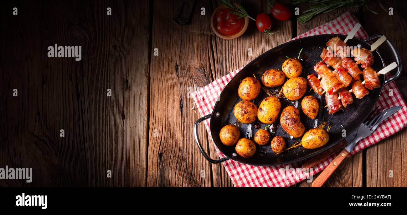 Rustic dates wrapped in bacon and young roasted potato Stock Photo - Alamy