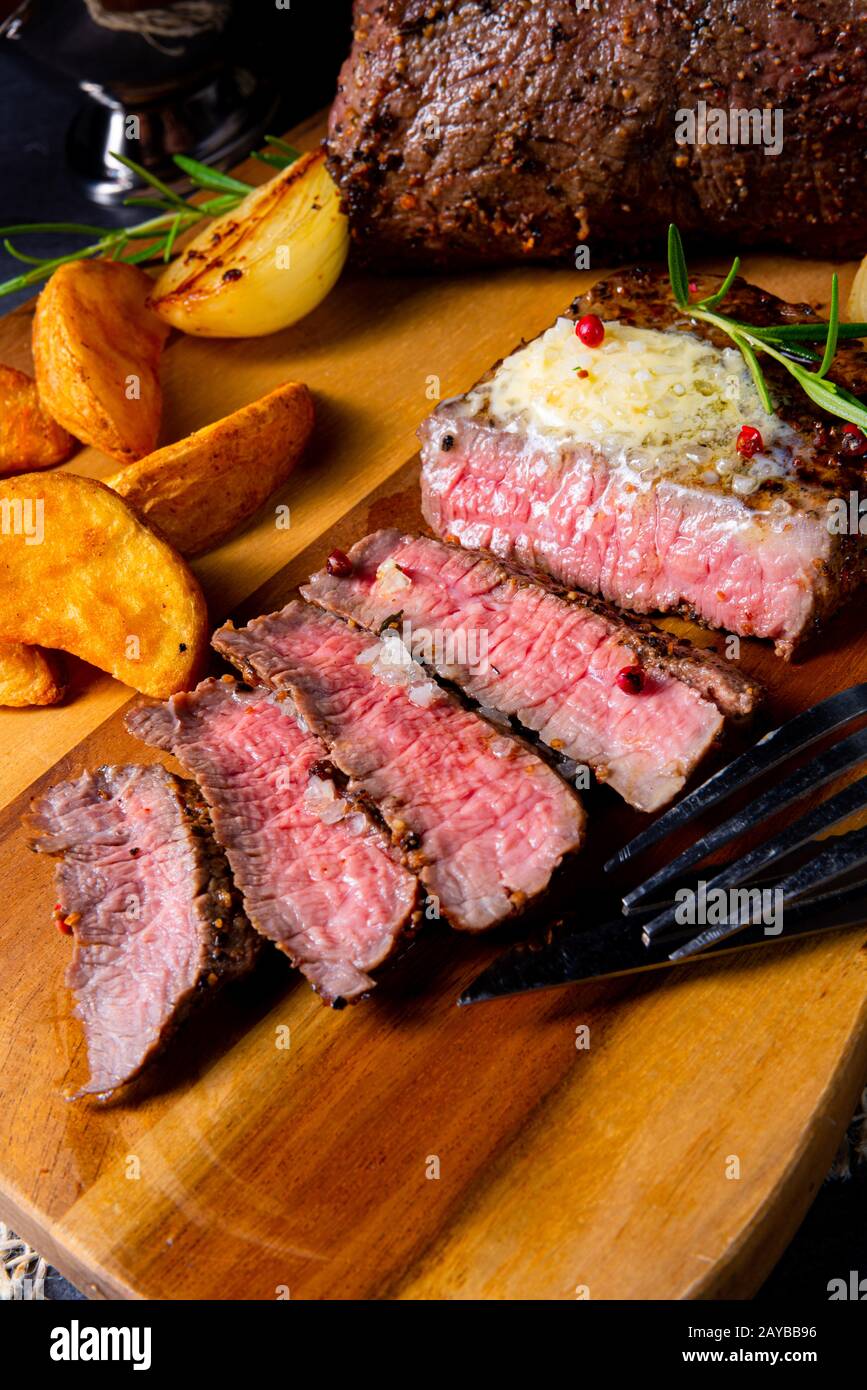 rustic medium butter beef steak with herbs and potato wedges Stock ...