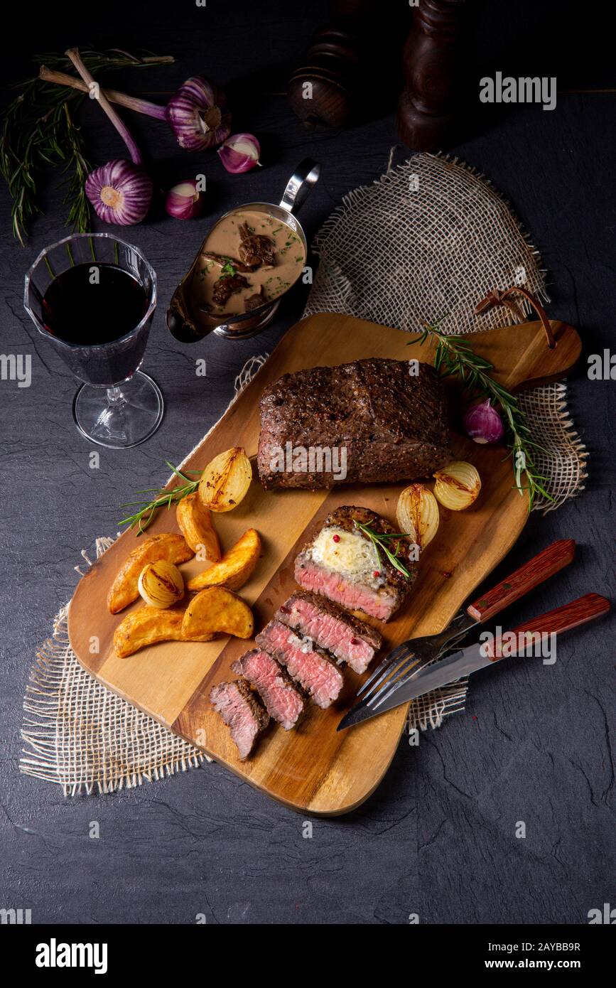 rustic medium butter beef steak with herbs and potato wedges Stock ...