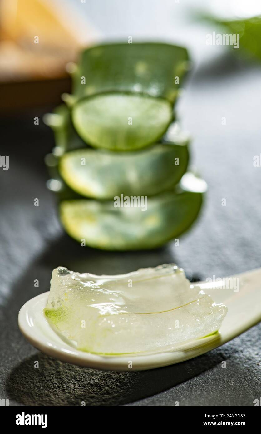 Aloe vera slices on dark background and spoon with aloe gel. Health and ...