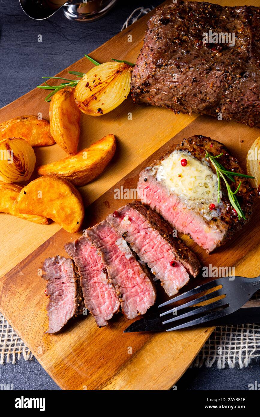 rustic medium butter beef steak with herbs and potato wedges Stock ...