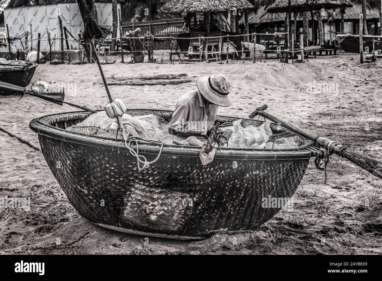 Fisherman fixing net sitting in a boat Stock Photo - Alamy