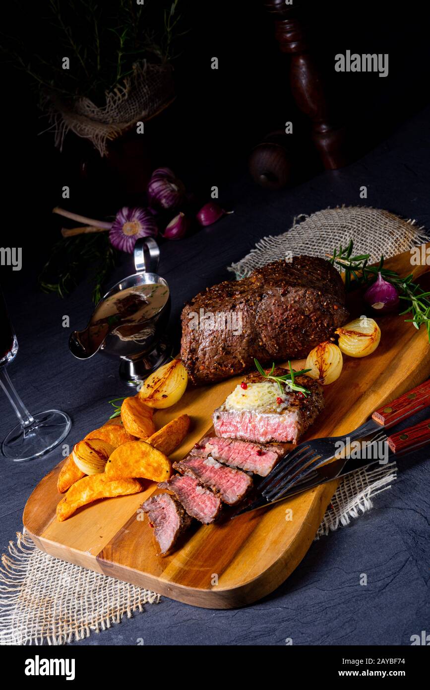 rustic medium butter beef steak with herbs and potato wedges Stock ...