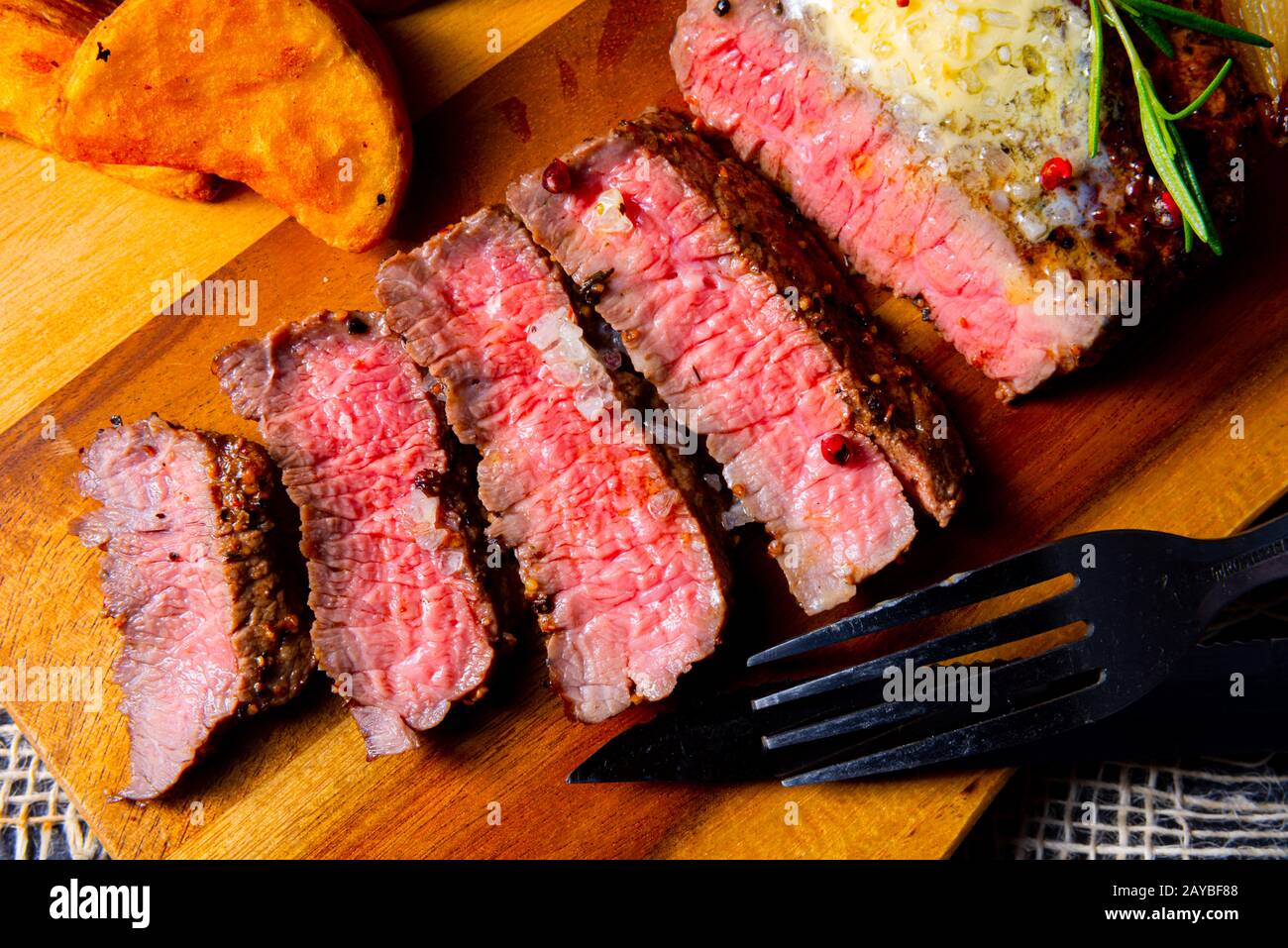 rustic medium butter beef steak with herbs and potato wedges Stock ...