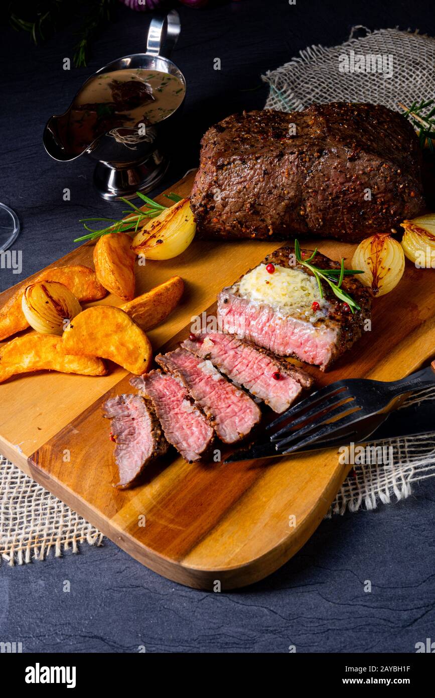 rustic medium butter beef steak with herbs and potato wedges Stock ...
