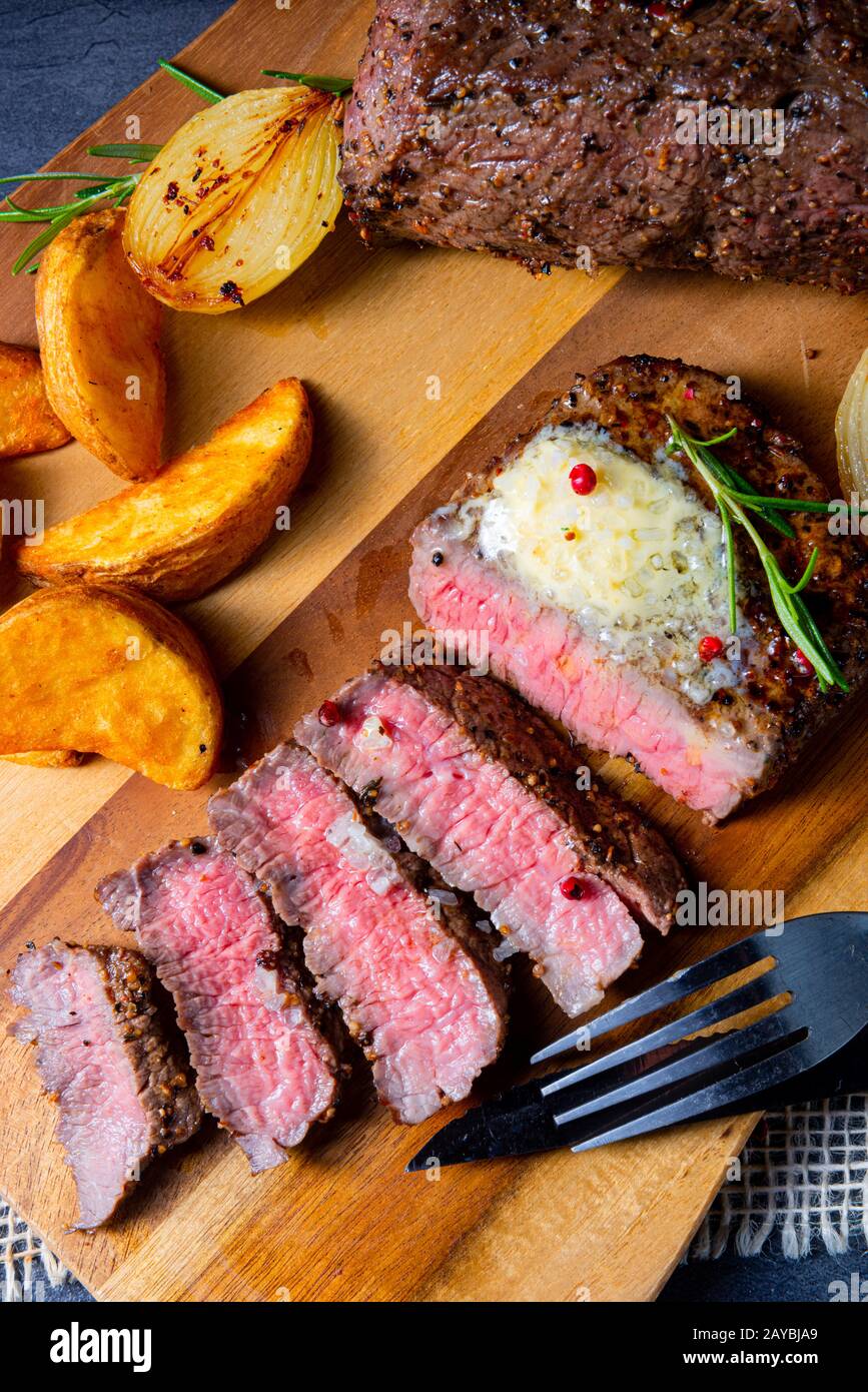 rustic medium butter beef steak with herbs and potato wedges Stock ...
