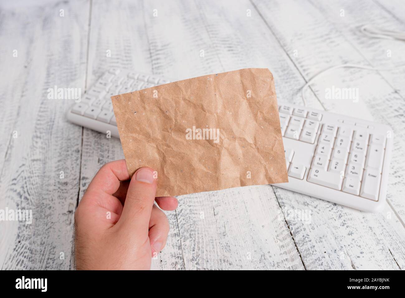 Man holding an empty rectangle shaped paper note, white keyboard in the ...