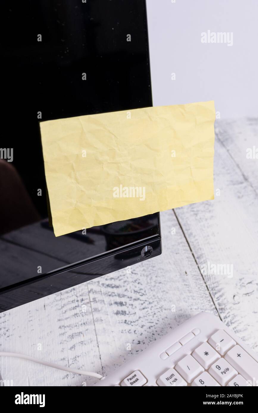 Notation paper stick to black computer screen near white keyboard above ...