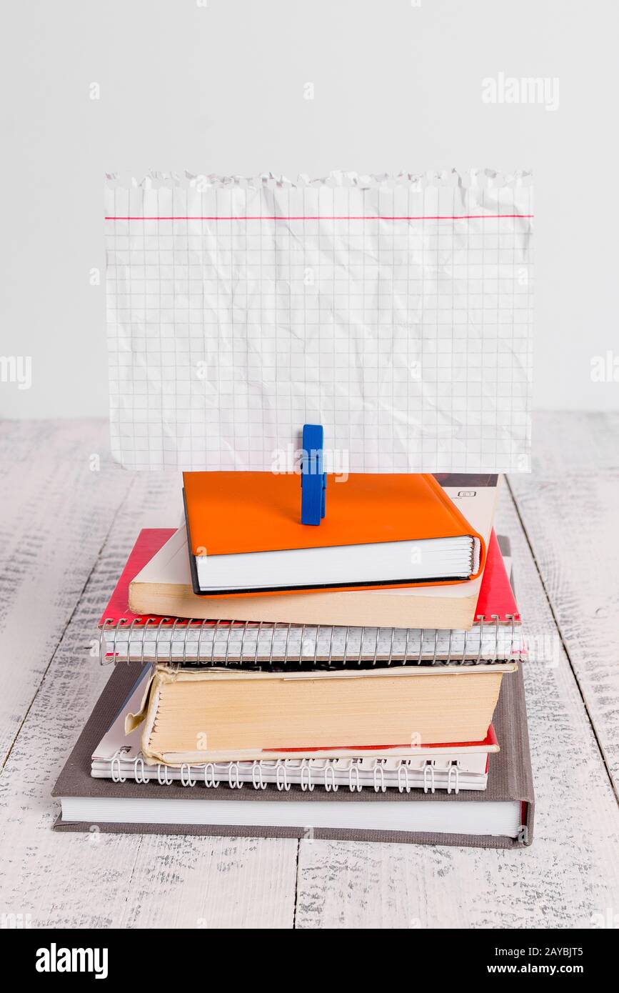 Square shaped paper above a pile of notebooks fixed by a blue ...