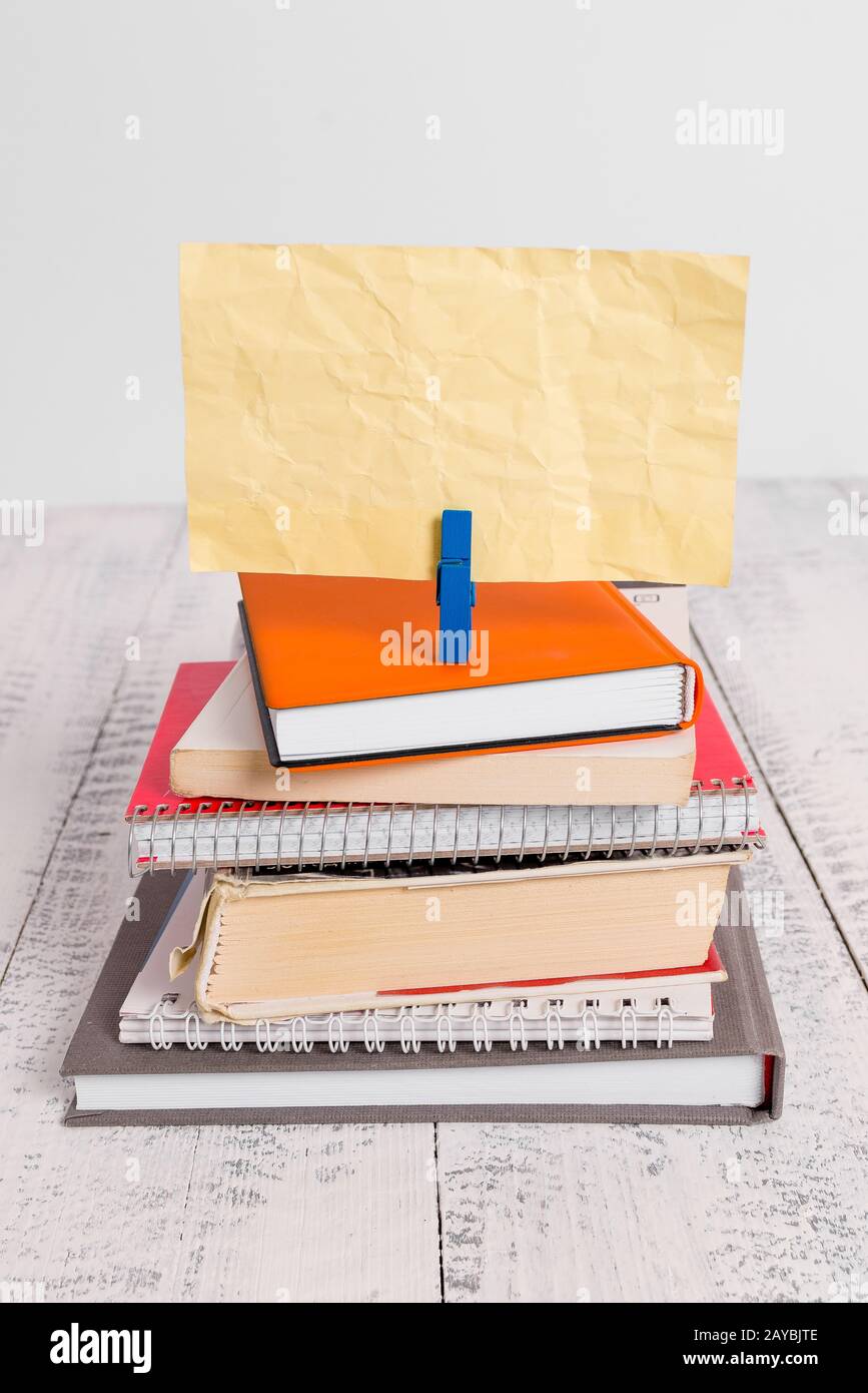 Square shaped paper above a pile of notebooks fixed by a blue ...