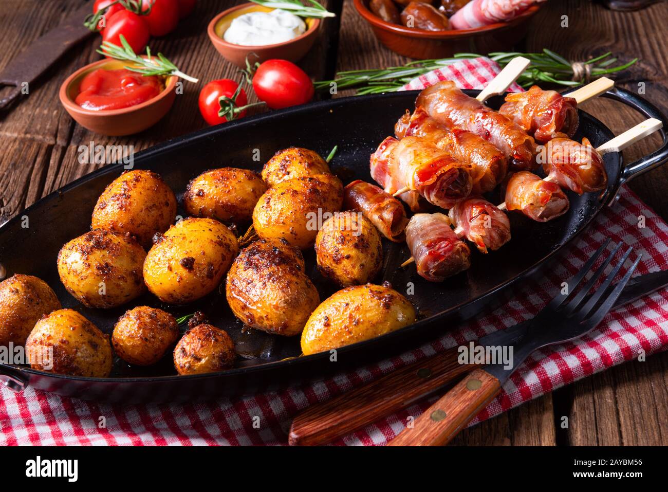 Rustic dates wrapped in bacon and young roasted potato Stock Photo - Alamy