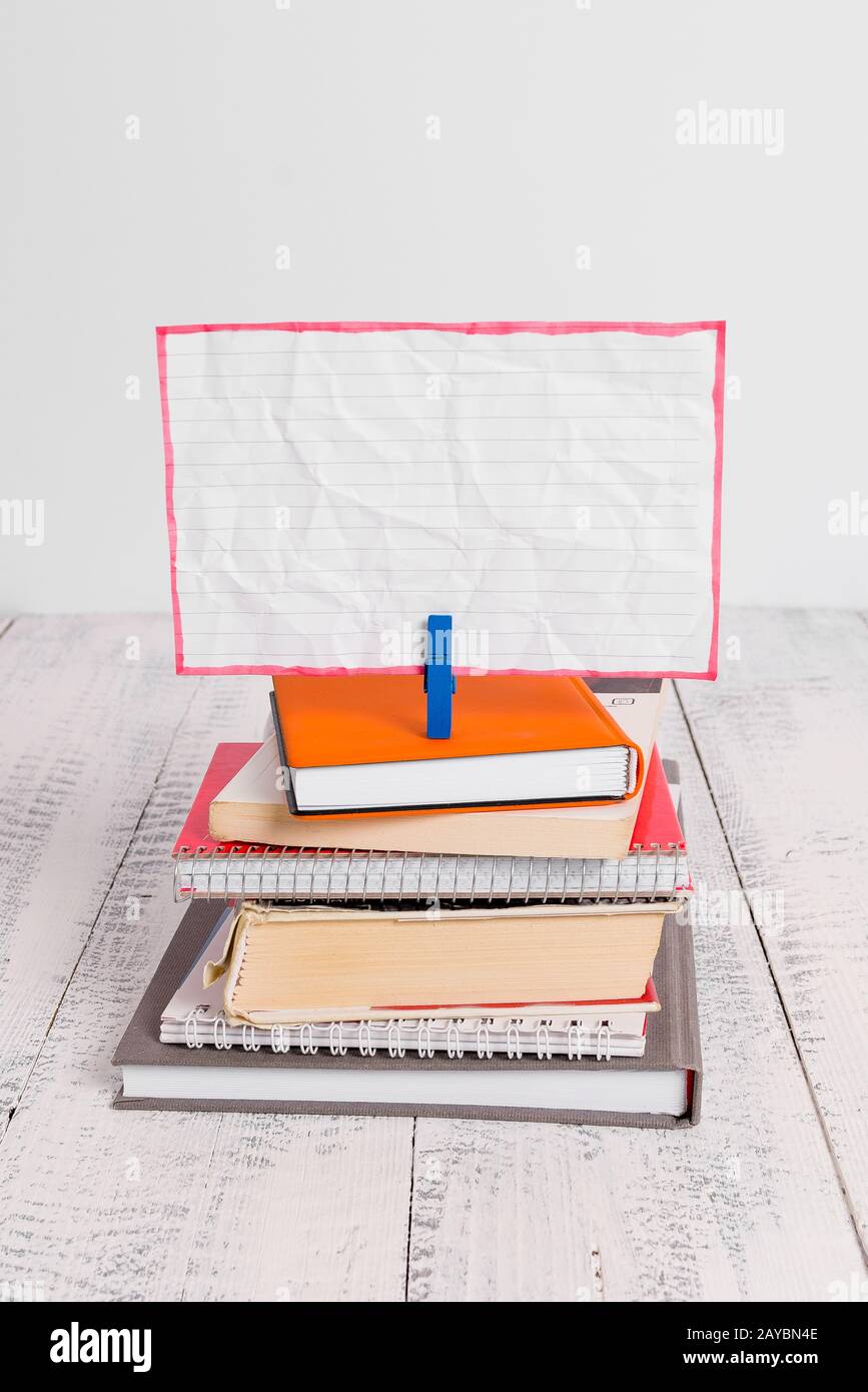 Square shaped paper above a pile of notebooks fixed by a blue ...