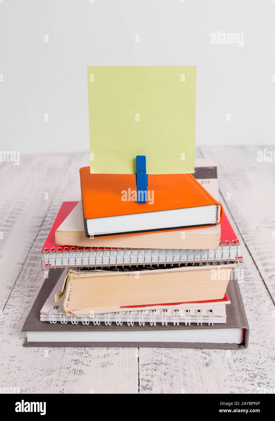 Square shaped paper above a pile of notebooks fixed by a blue ...