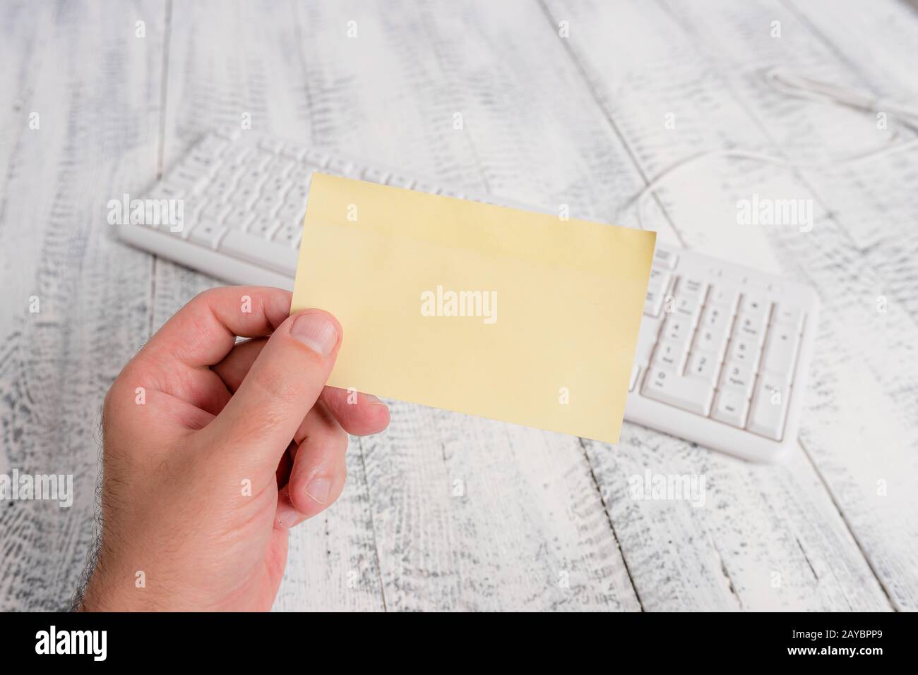 Man holding an empty rectangle shaped paper note, white keyboard in the ...