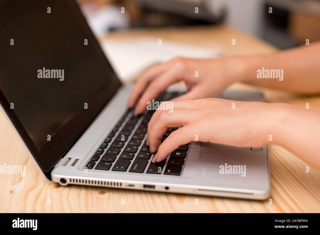 Young lady using a gray laptop computer and typing in the black ...