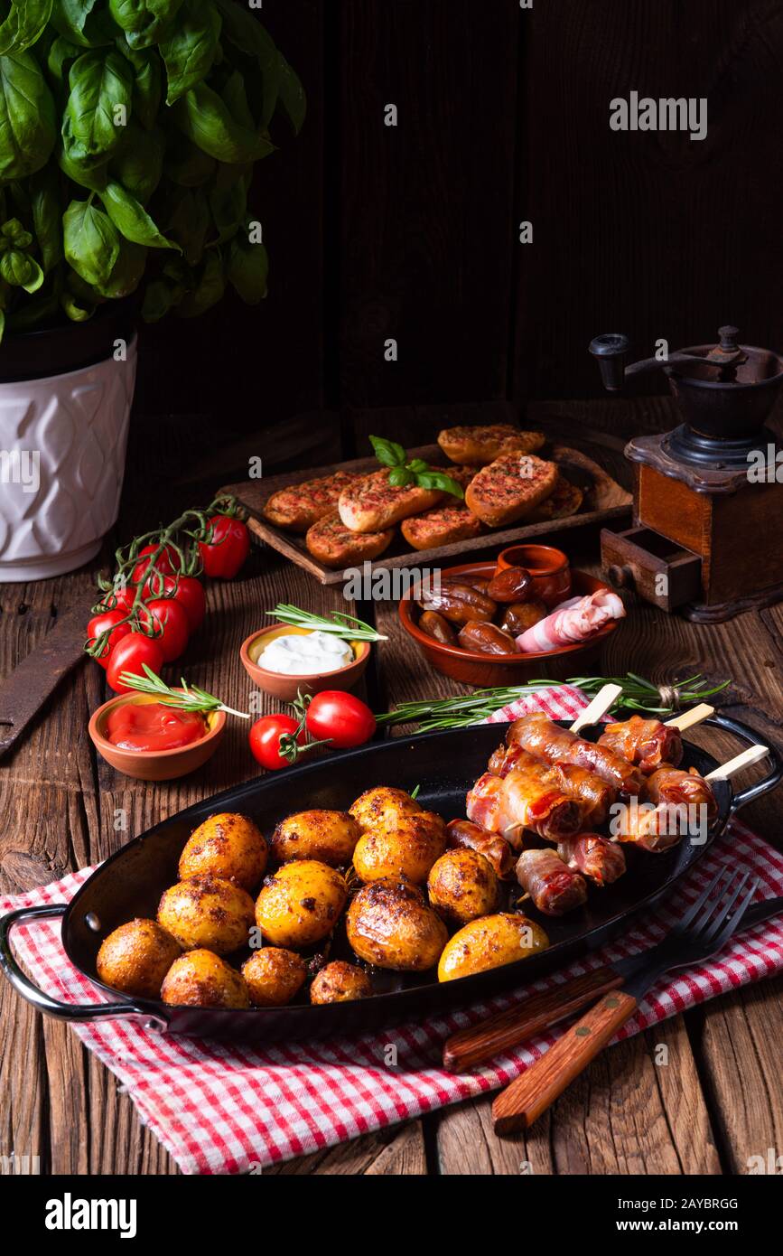 Rustic dates wrapped in bacon and young roasted potato Stock Photo - Alamy