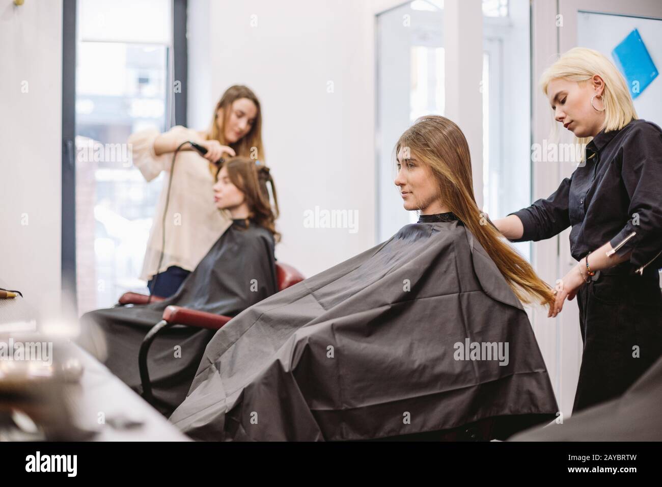 beautiful woman combing wet hair. stylist brushing woman hair in salon ...