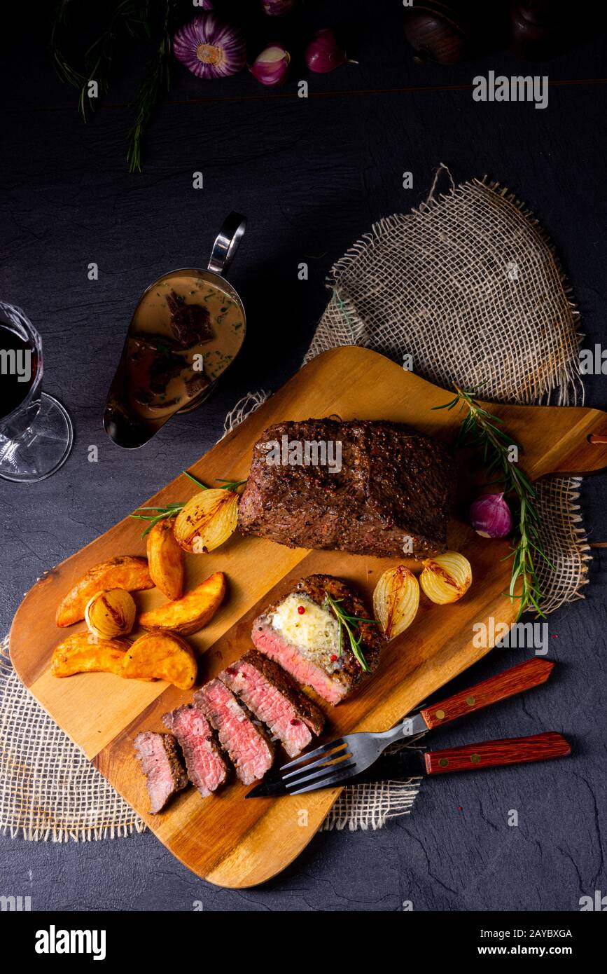 rustic medium butter beef steak with herbs and potato wedges Stock ...