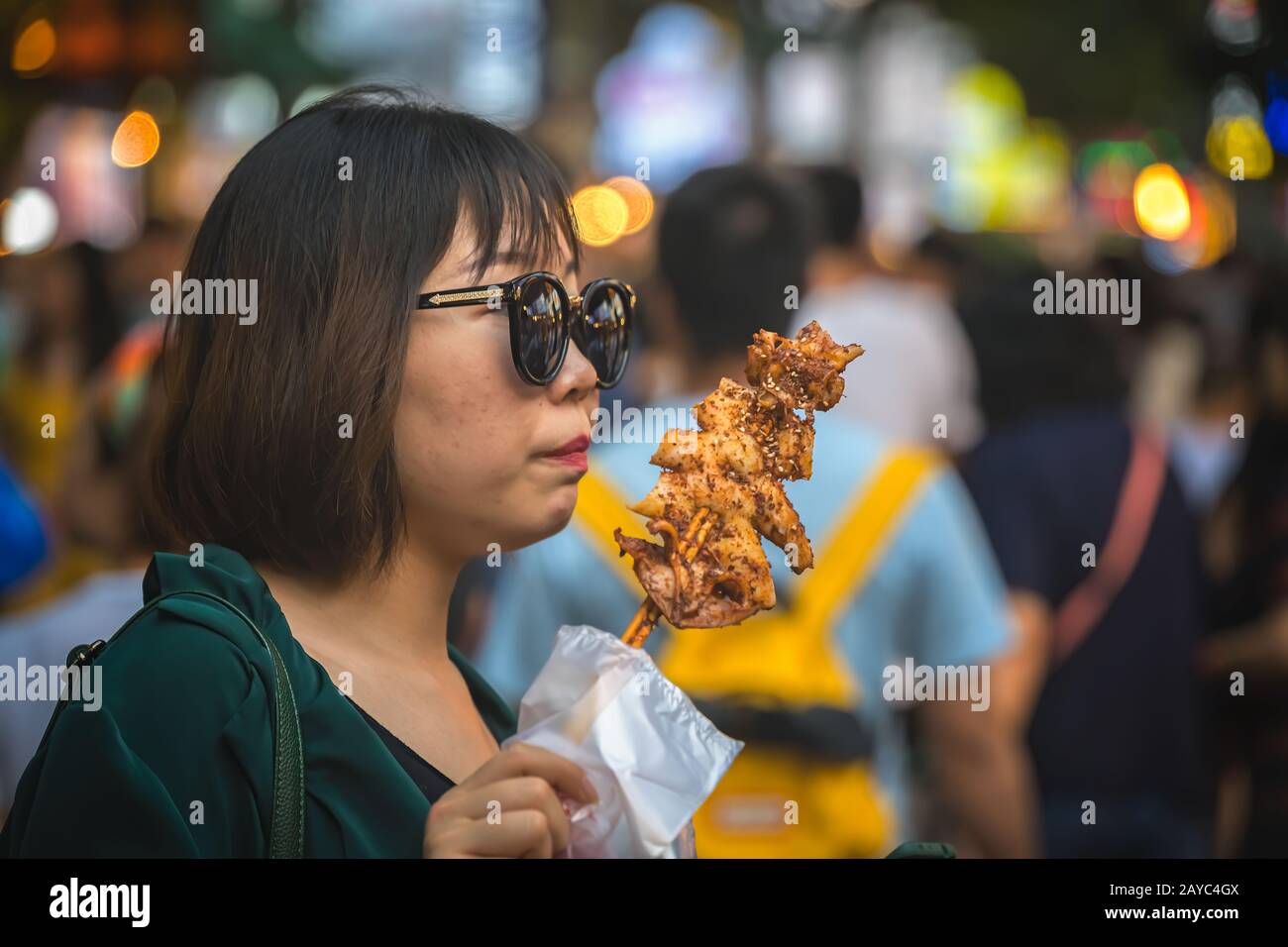 Chinese woman eating snack from a stick Stock Photo - Alamy