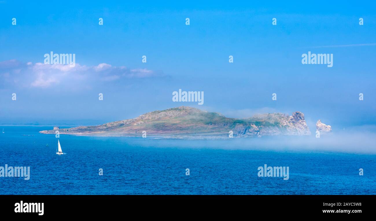Low lying mist covering Irelands Eye island, view from Howth, Ireland ...