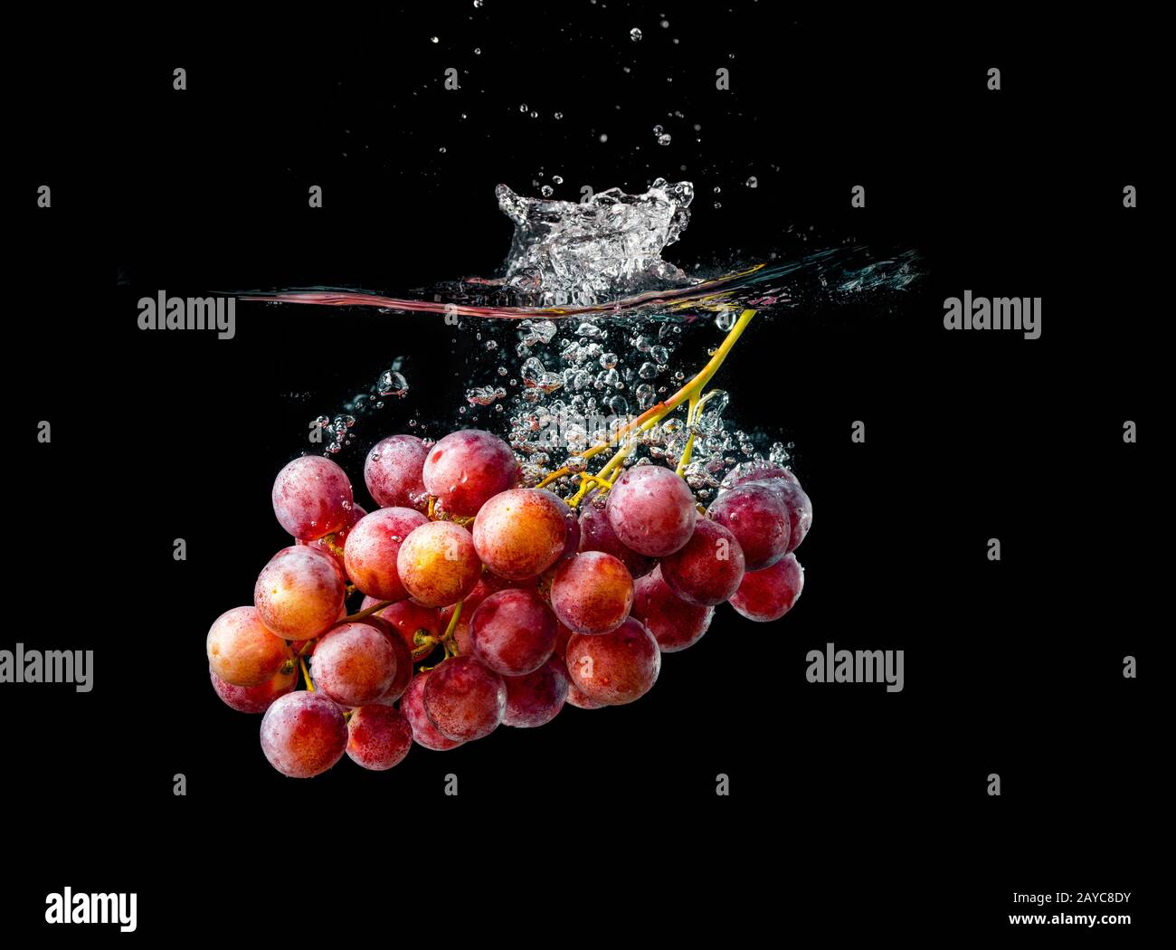 Isolated Red grapes splashing and sinking in water on black background ...
