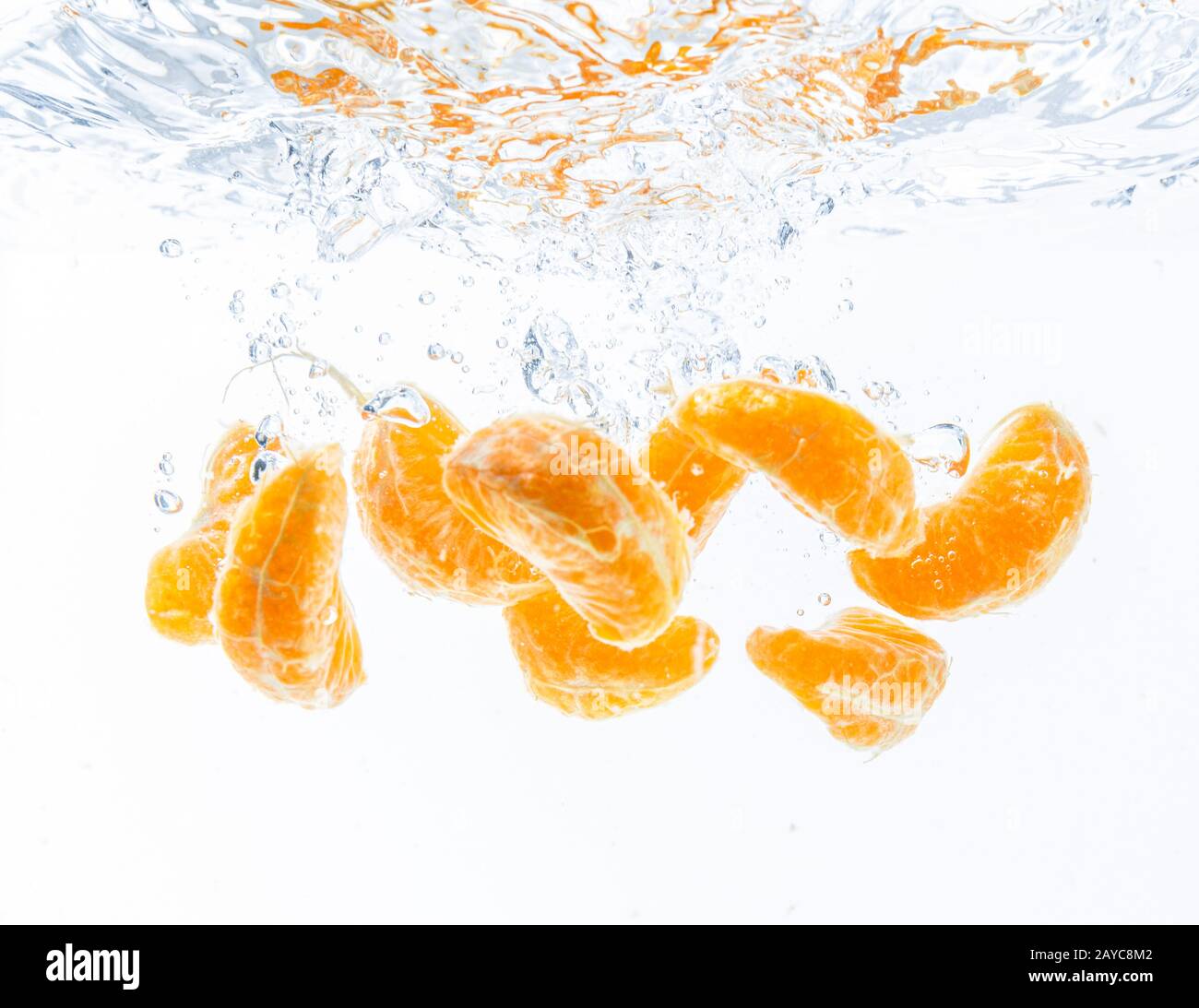 Isolated falling orange segments into water. Peeled pieces of orange ...