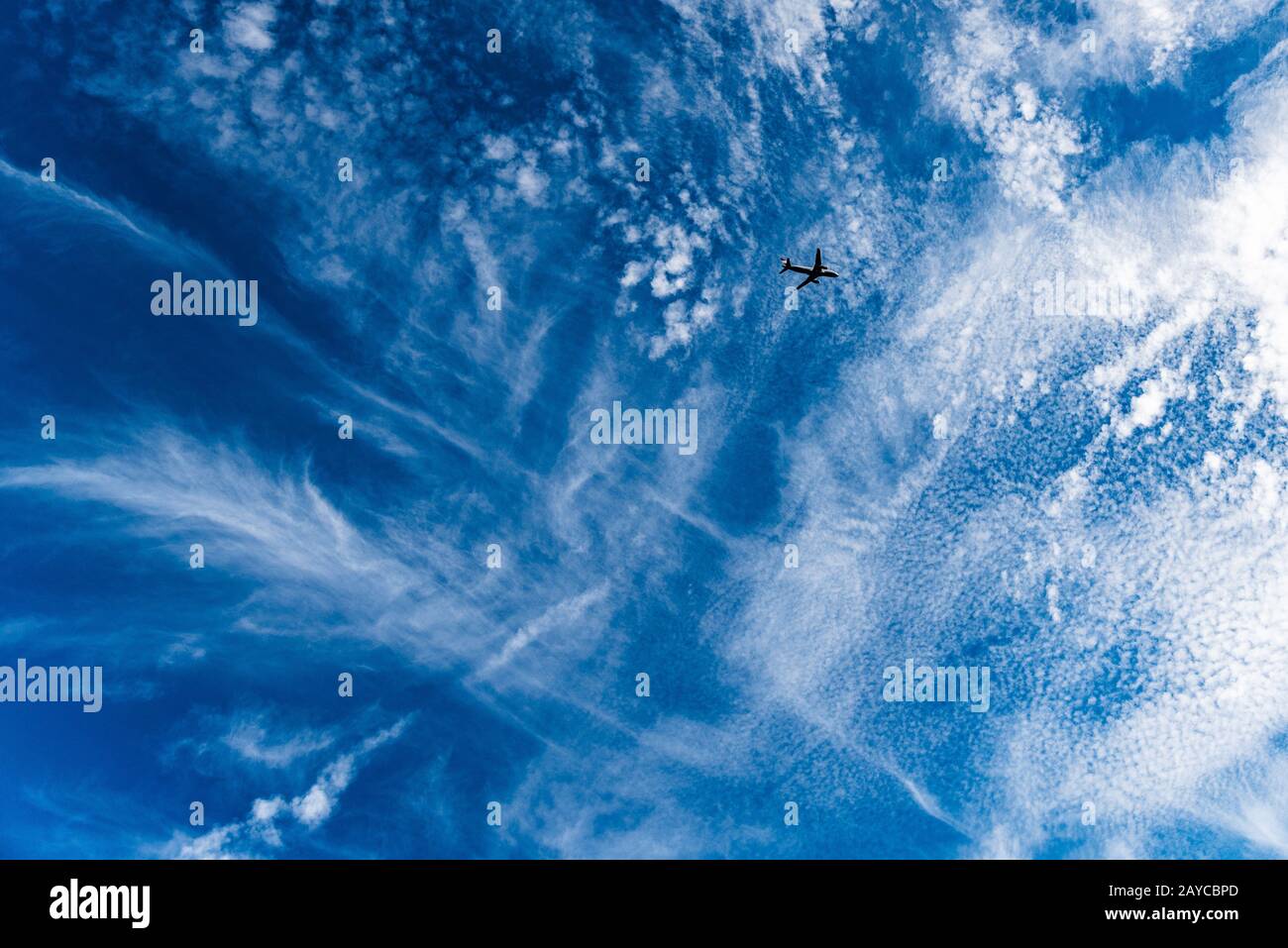 Blue sky with white stretched clouds and passenger plane flying high ...
