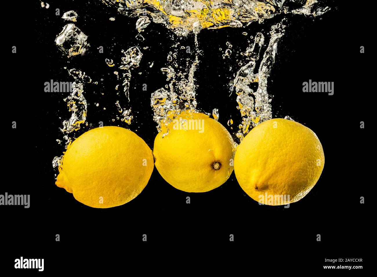 Fresh yellow lemons in water splash on black background with lots of ...
