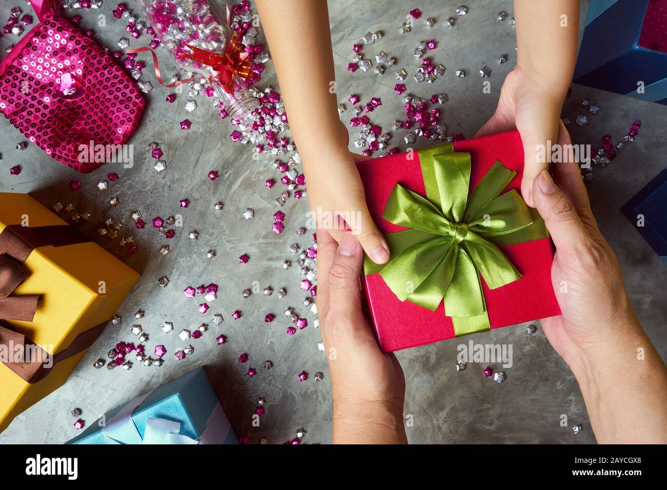 Close up hands of parent giving a Christmas gift to child with colorful ...