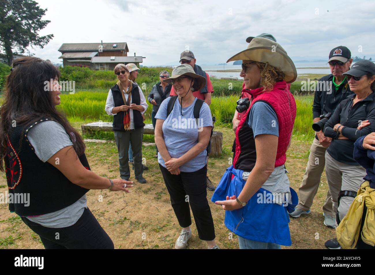 Tlingit people explaining a totem pole to tourists in the village of ...