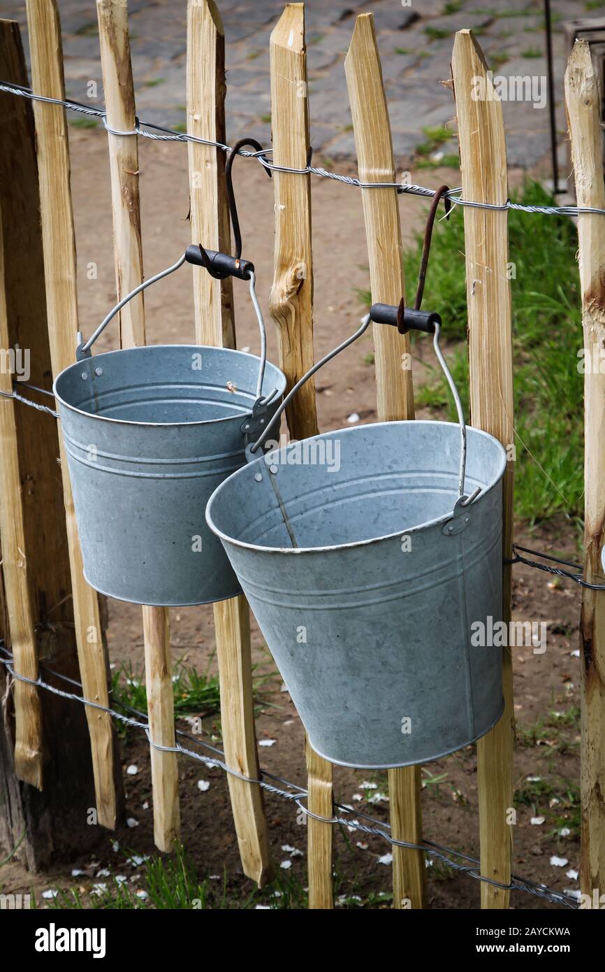 Two enamel buckets are attached to a fence Stock Photo - Alamy