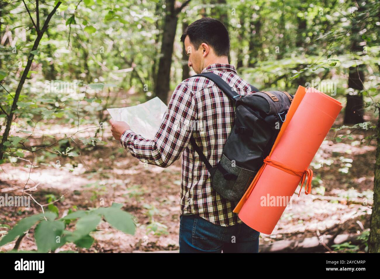 Man with Backpack and map searching directions in wilderness area ...