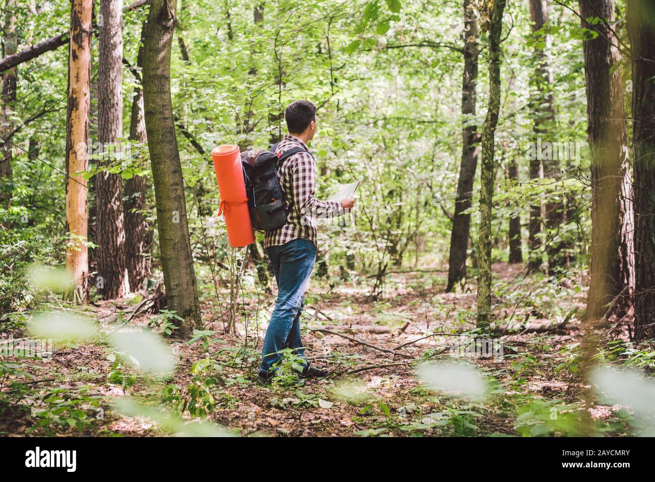 Man with Backpack and map searching directions in wilderness area ...