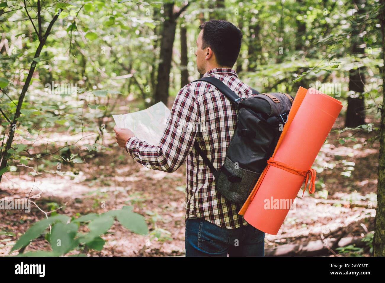 Man with Backpack and map searching directions in wilderness area ...