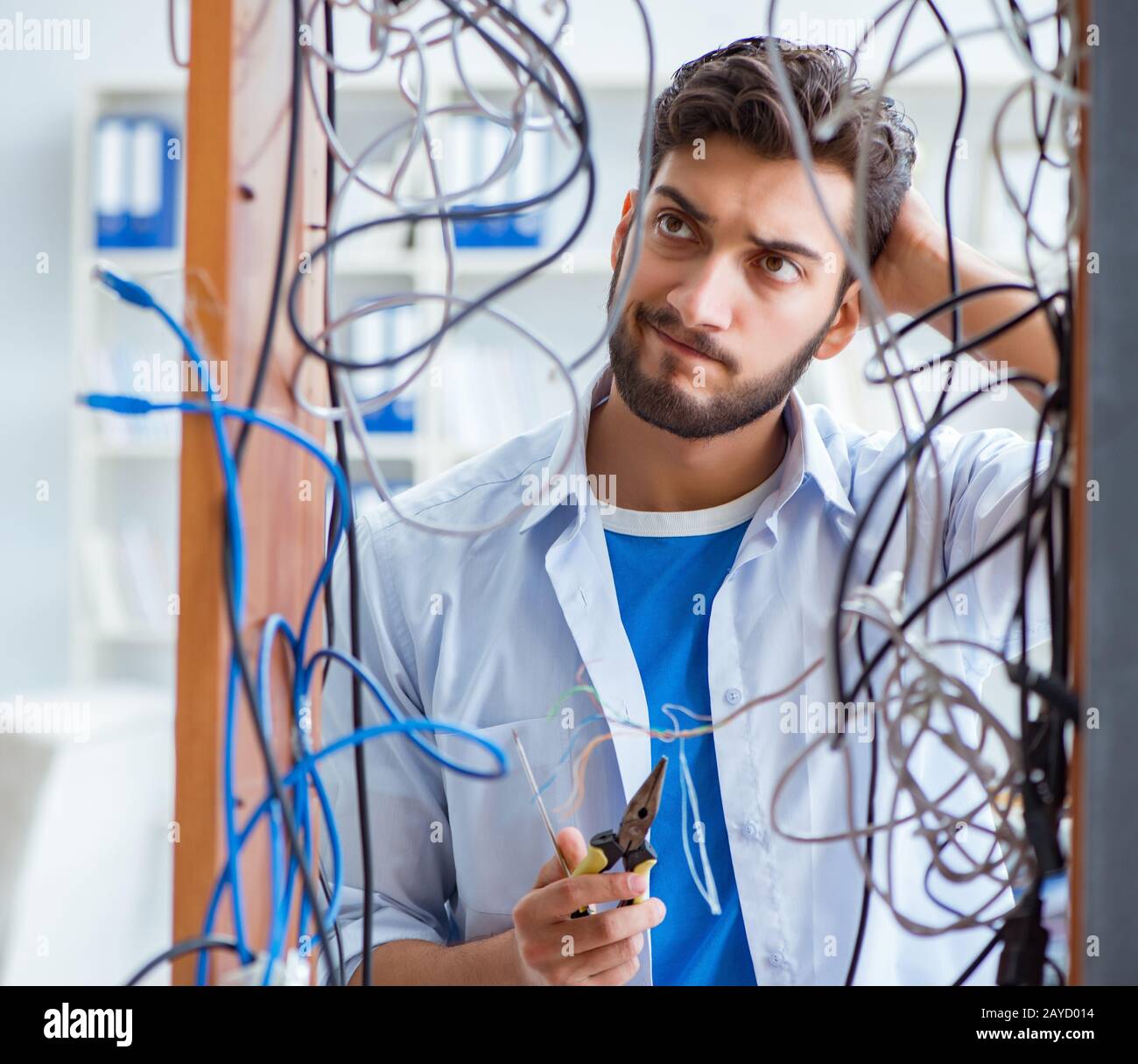 Electrician trying to untangle wires in repair concept Stock Photo - Alamy