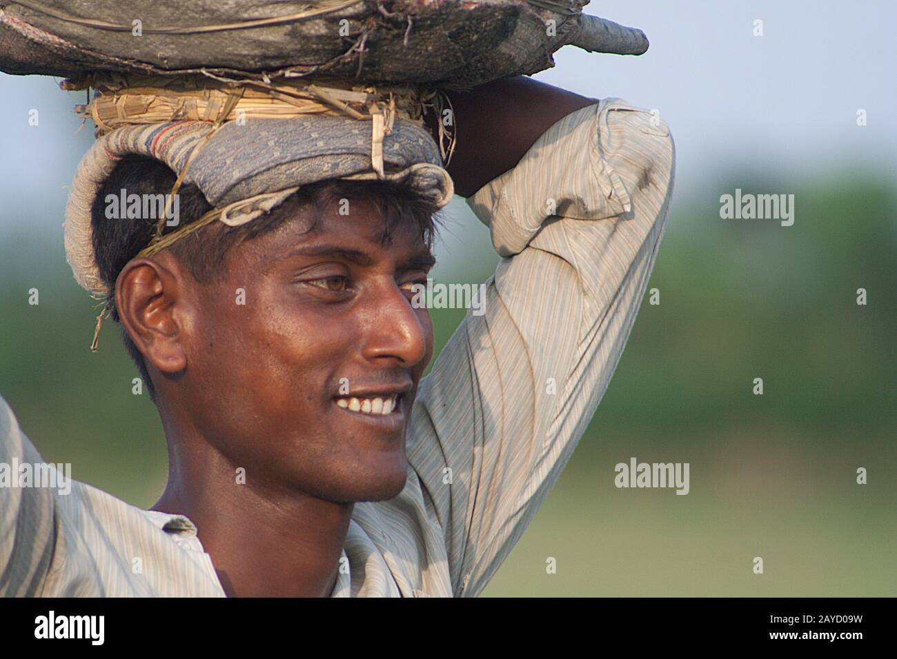 A day labourer carries a basket of soil on his head. Khulna, Bangladesh ...