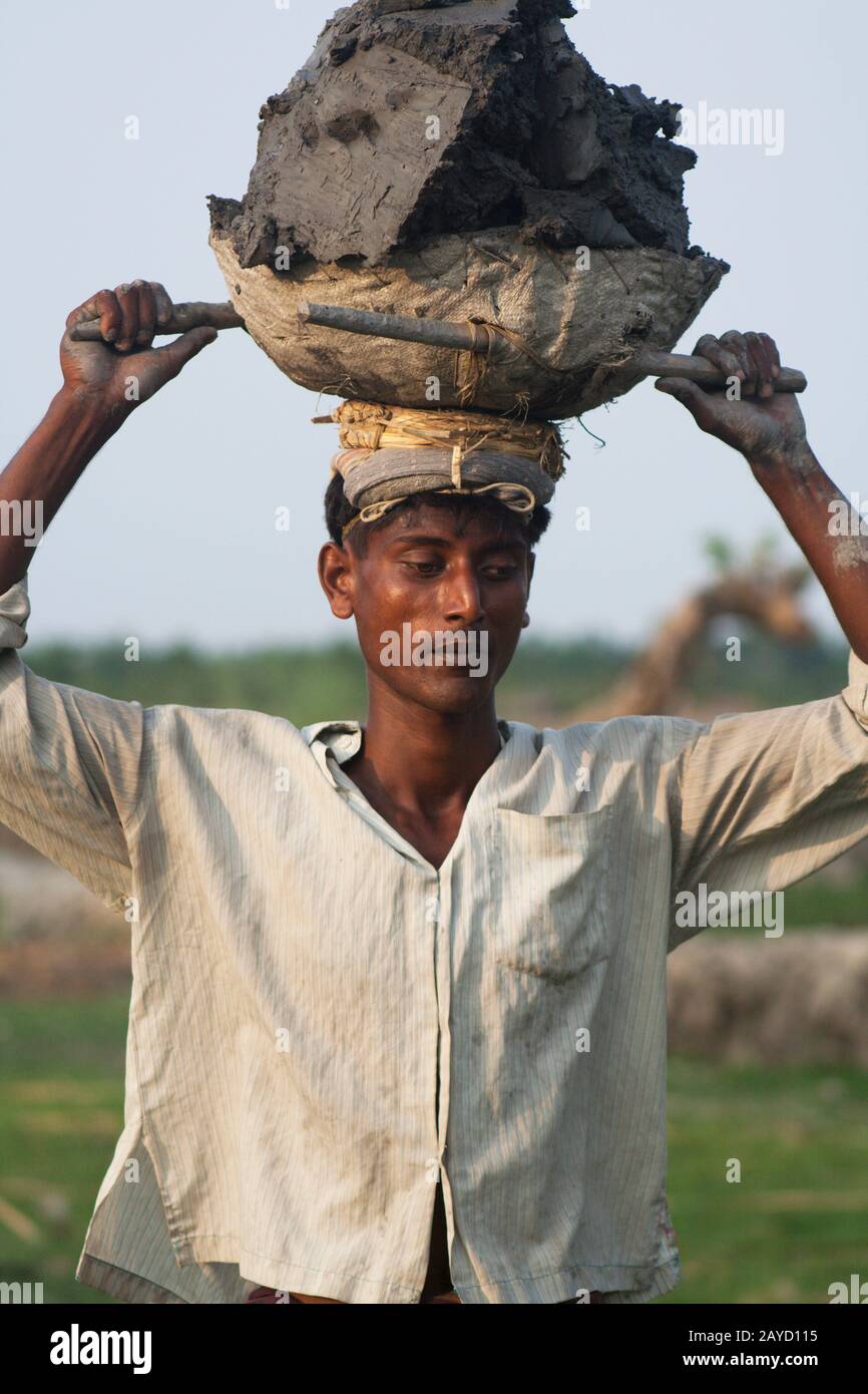 A day labourer carries a basket of soil on his head. Khulna, Bangladesh ...