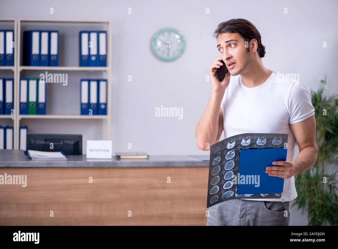 Young man at hospital reception desk Stock Photo - Alamy